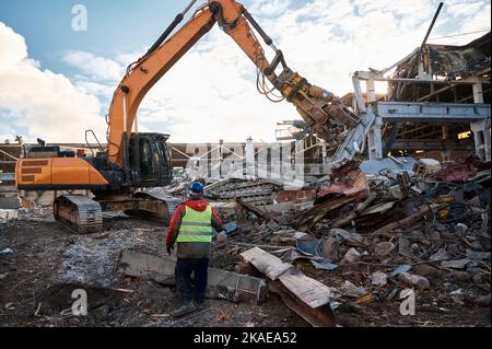 Excavator destroyer removes debris under worker control Stock Photo - Alamy
