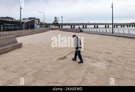 Maintenance workman raking sand on urban beach, Dundee Waterfront or ...