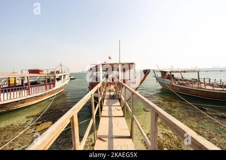 A row of empty old traditional dhow ships docked by the shore at Doha ...