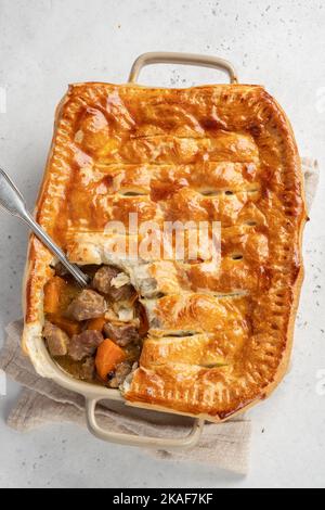 English beef steak pie with crispy puff pastry close-up in a baking ...