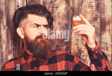Suspicious drink concept. Barman with beard and serious face looks at ...