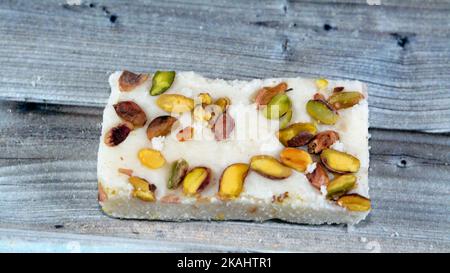 A piece of soft coconut Egyptian candy covered with pistachios ...