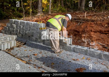 Construction worker building retaining block wall being built on new ...