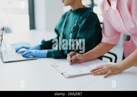 Asian doctors and nurses using computers and documents to view patient ...
