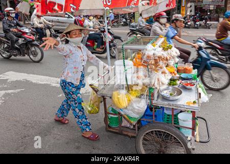 Vietnamese hawker wearing bamboo hat selling food from pannier in ...