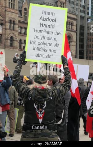 Anti-immigration protesters watch a group of counter-protesters outside ...