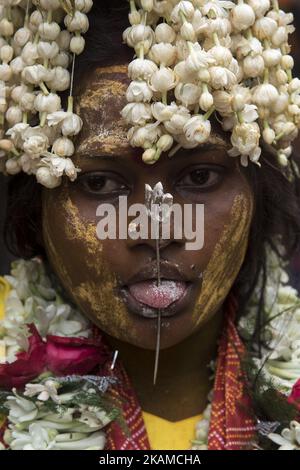 A devotee woman is getting her tongue pierced as a ritual of the vel ...