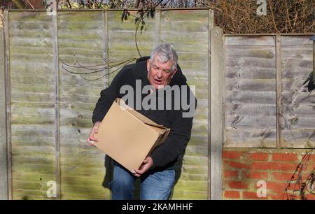 Old or elderly man lifting a heavy box and hurting himself. Box too ...