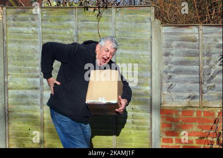 Old or elderly man lifting a heavy box and hurting himself. Box too ...