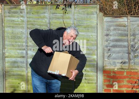 Old or elderly man lifting a heavy box and hurting himself. Box too ...