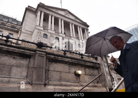 A pedestrian with an umbrella walks past the Bank of England. UK braces ...
