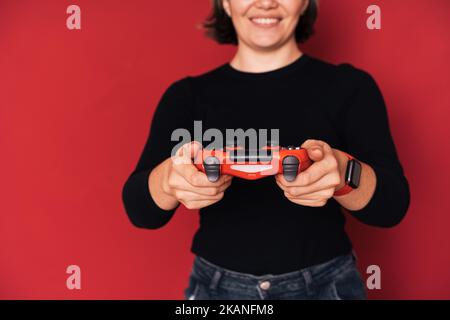 Lady holding gamepad in her hand against red background Stock Photo - Alamy