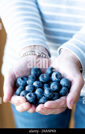 A woman holding a recommended daily portion size of blueberries. The ...