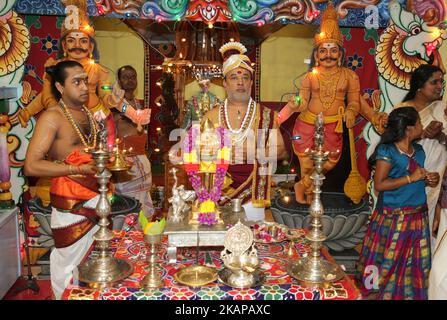 Tamil Hindu priests perform special prays as they bathe a large stone ...