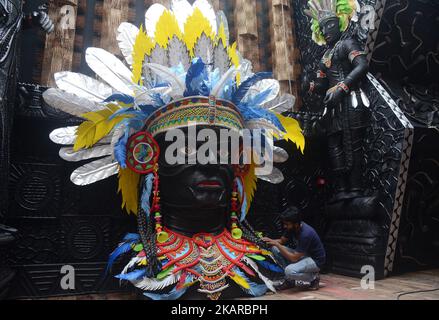 An Indian artisan prepares the statue of Red Indians in a Puja pandal ...