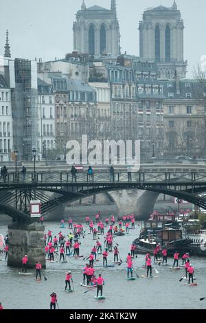 Paddle boarders pass near the Pont de Bercy bridge as they participate ...