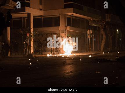 A petrol bomb explodes next to riot police during clashes following an ...