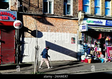 Figure passing by rundown shops in Southall Greater London England UK ...