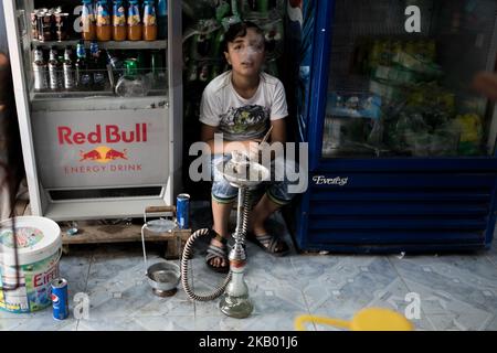 A boy working in a supermarket in Qamishli, Syria smokes a hookah in ...