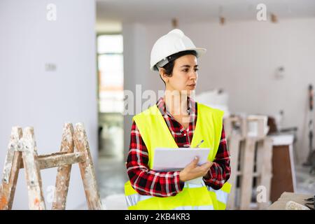 Woman engineer checking documents during repair works indoors Stock ...