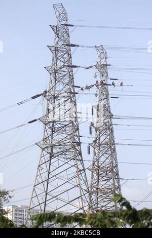 Workers assemble electricity installations on high voltage towers for ...