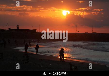 Palestinians watch the sunset on the shore of the Mediterranean Sea in ...