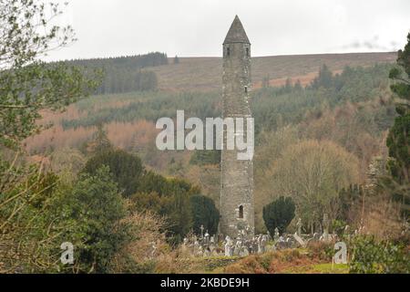 A view of an Irish round tower, tombstones and Celtic crosses inside an ...