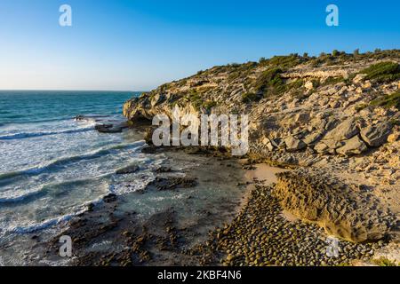 Scenic view of Waenhuiskrans sea-cave and rugged rocky shoreline at ...