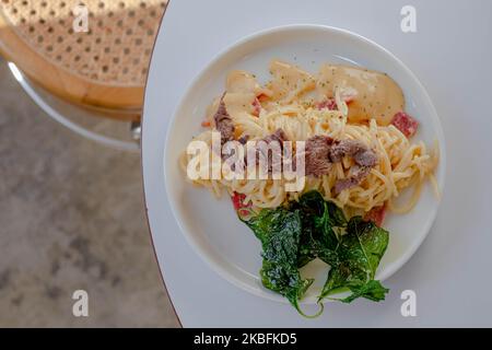 A plate of Rose Pasta Spaghetti with beef and spinach in a white table ...