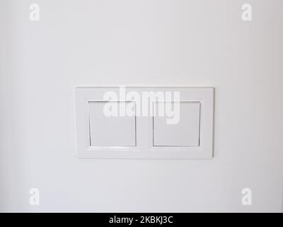 Double white plastic mechanical switches, installed on a white wall ...