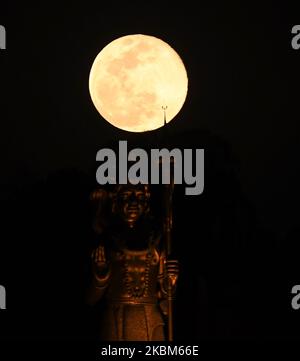 The rising supermoon crosses behind the Statue of Kailashnath Mahadev ...