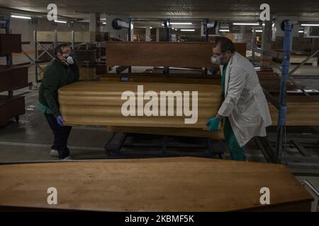 Workers moving coffins with the bodies of people who dead of ...