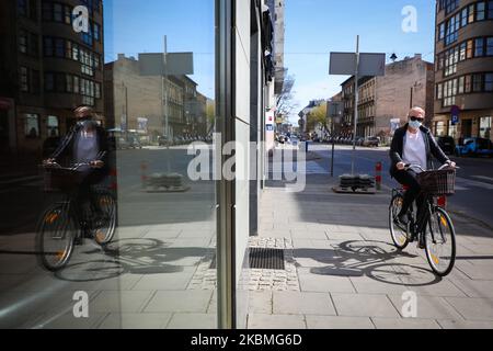 A person wears a mask as they ride a bicycle during a hot weather day ...