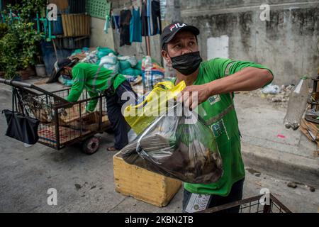 Garbage collectors load the dump trunk with household waste collected ...