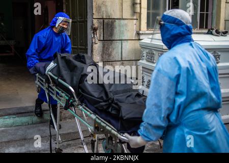 Funeral workers wearing personal protective equipment (PPE) burying a ...