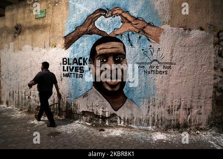 Palestinians walk past a mural , in Gaza City March 18, 2021. (Photo by ...