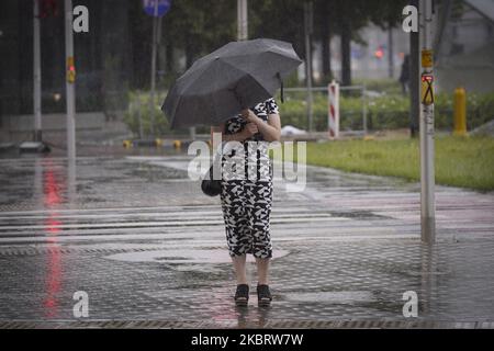 A woman with an umbrella is seen at a traffic stop on June 29, 2020 in ...