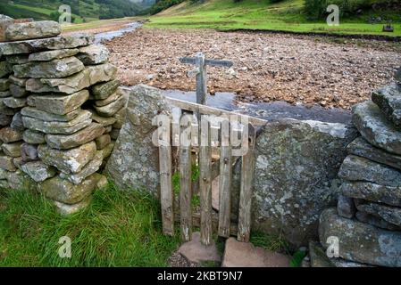 traditional stone gate or stile in a dry stone wall with flowers and ...