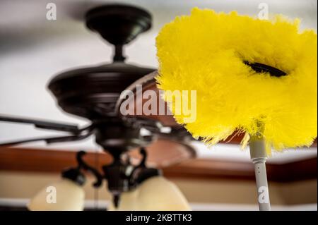 Using a wand feather duster to remove and clean dust from a ceiling fan ...