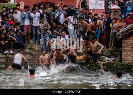 Nepalese people grab a goat on the side of a pond before sacrifice ...