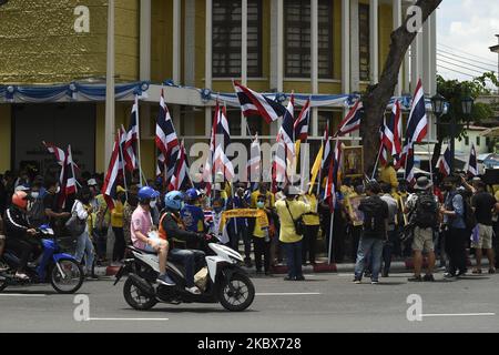 Thai royalists wearing face masks hold pictures of the royal family ...
