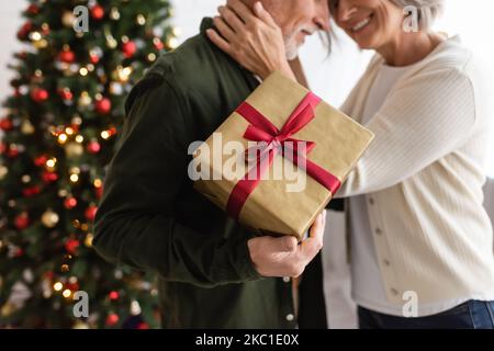 cropped view of happy and bearded middle aged man holding wrapped ...