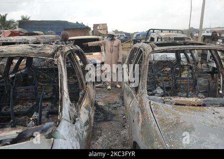 People stand next to burned cars after a tanker exploded on Lagos ...