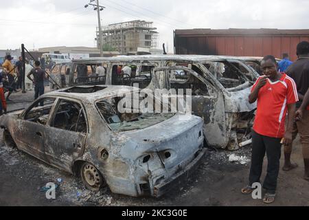 People stand next to burned cars after a tanker exploded on Lagos ...