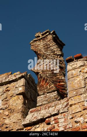 An Ancient weathered ornate damaged chimney stack against blue sky ...