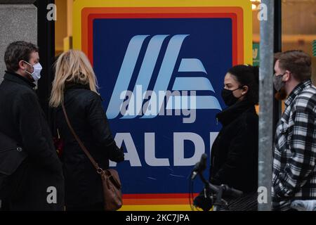 People wearing face mask walk past by a caricaturist stand in the ...