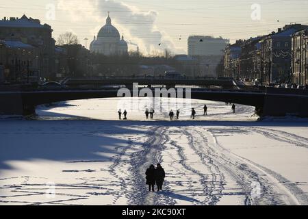 People walk on the frozen Fontanka River during a snowfall in St ...