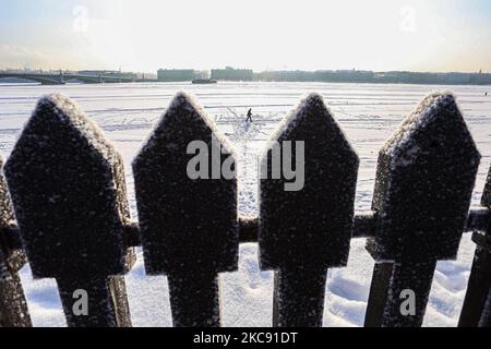 A man walks on the ice of the Neva River during sunset in St ...