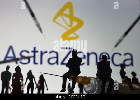 Medical syringes and small figurines of people are seen in front of the ...