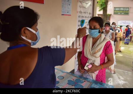 A health worker checks temperature of a citizens who standing in a long ...